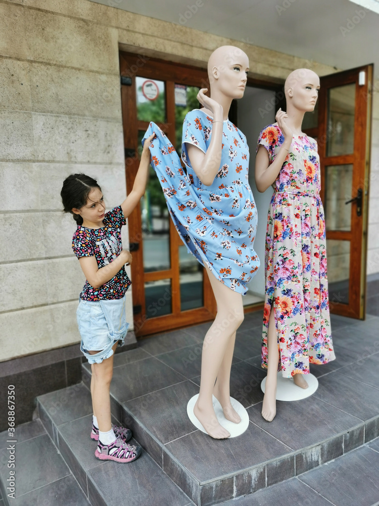 Little girl looks under the dress of a mannequin Stock Photo | Adobe Stock