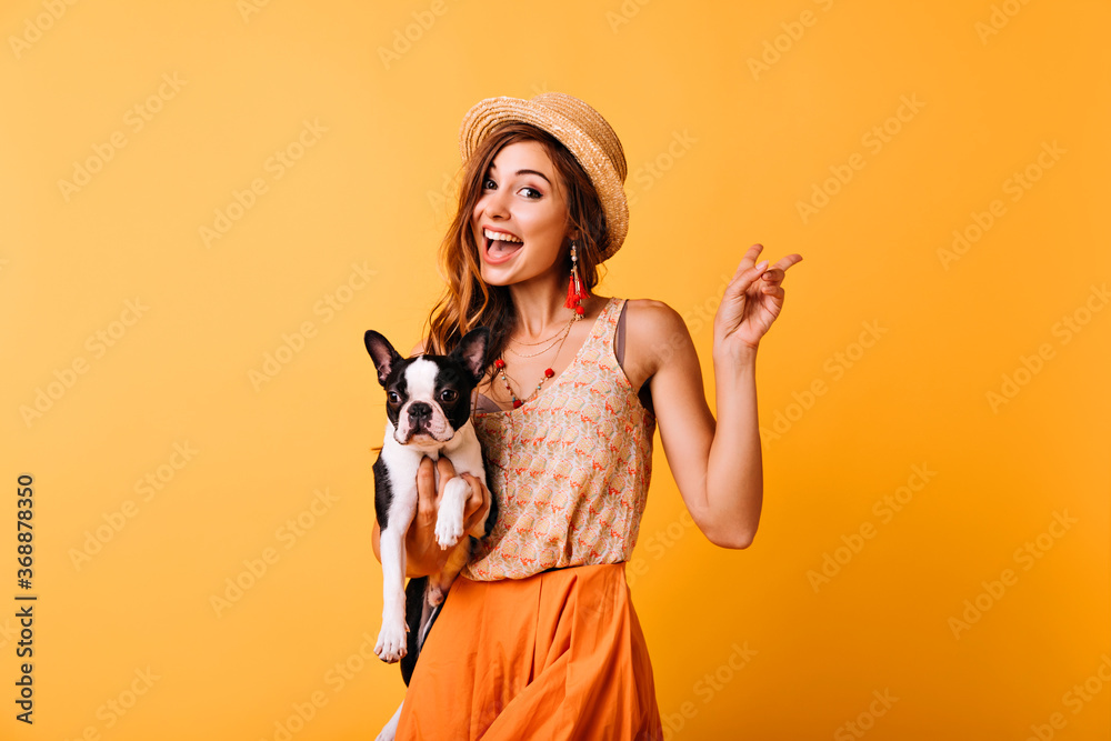 Charming red-haired girl in vintage hat holding french bulldog. Indoor ...