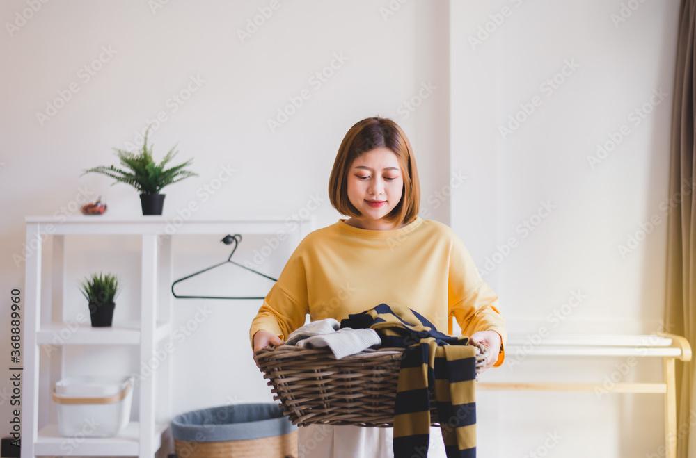 Young happy asian woman doing laundry with basket at home Stock Photo ...