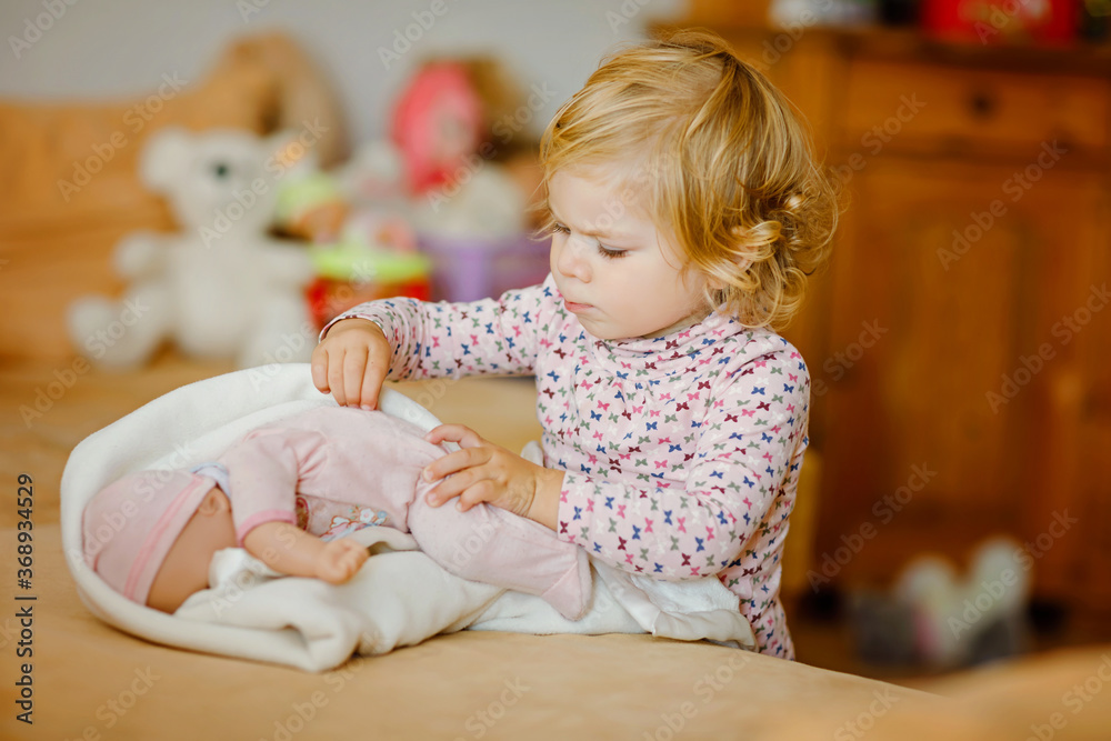 Adorable cute little toddler girl playing with doll. Happy healthy baby ...