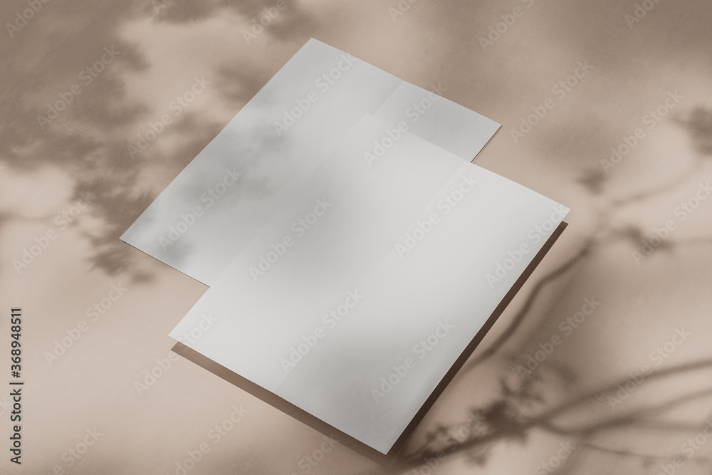 Two sheets of A4 paper lying on top of each other on a light beige ...