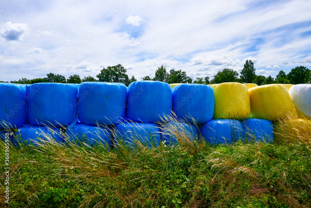 Resmo, Oland, Sweden Yellow and blue hay bales stacked in a field ...