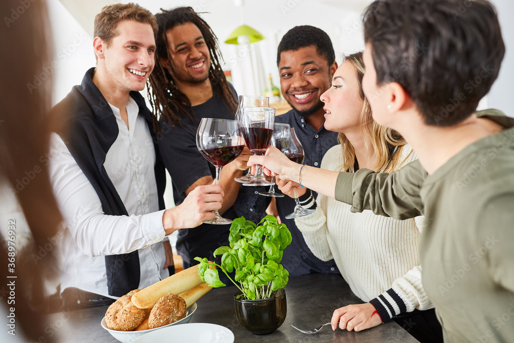 Friends toasting with glass of red wine in kitchen Stock Photo | Adobe ...