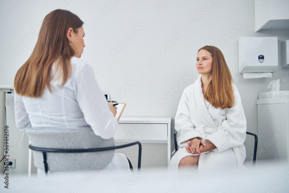 Ladies in white robes sitting on the chairs while having conversation ...