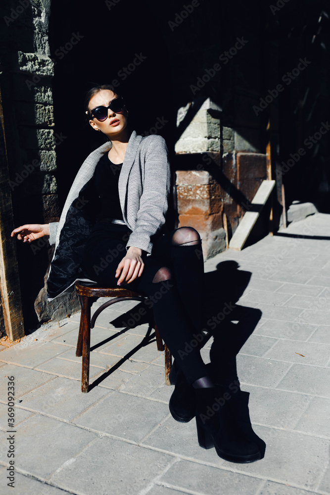 Fashion model sitting on chair and looking away. Stock Photo | Adobe Stock