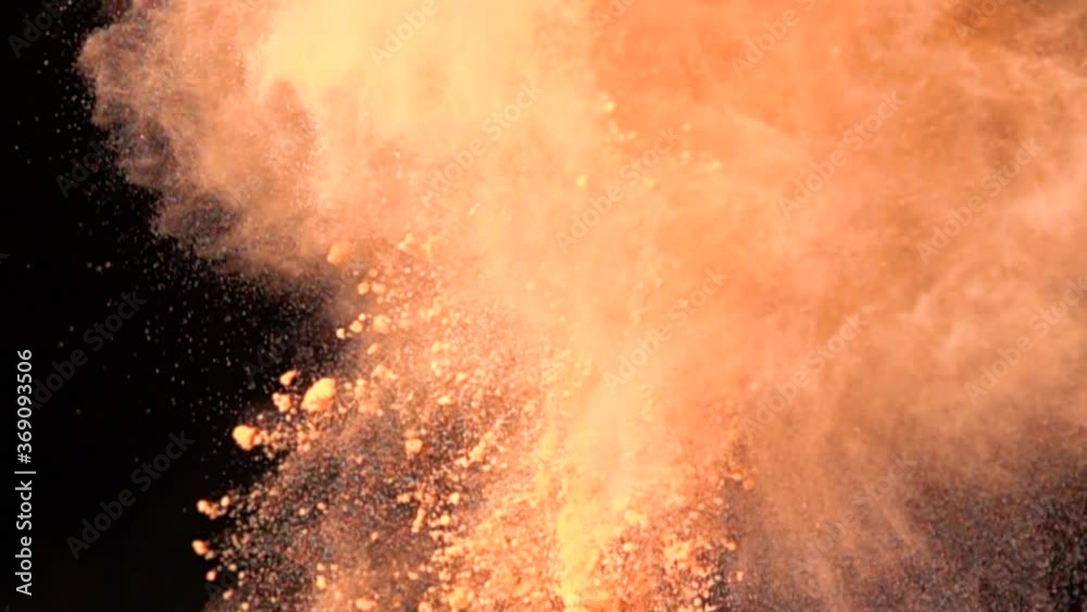 Super slow motion explosion of colorful orange powder on dark isolated ...