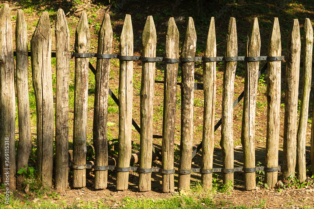 Old fence made of sharpened wooden logs. Protective structure for the ...
