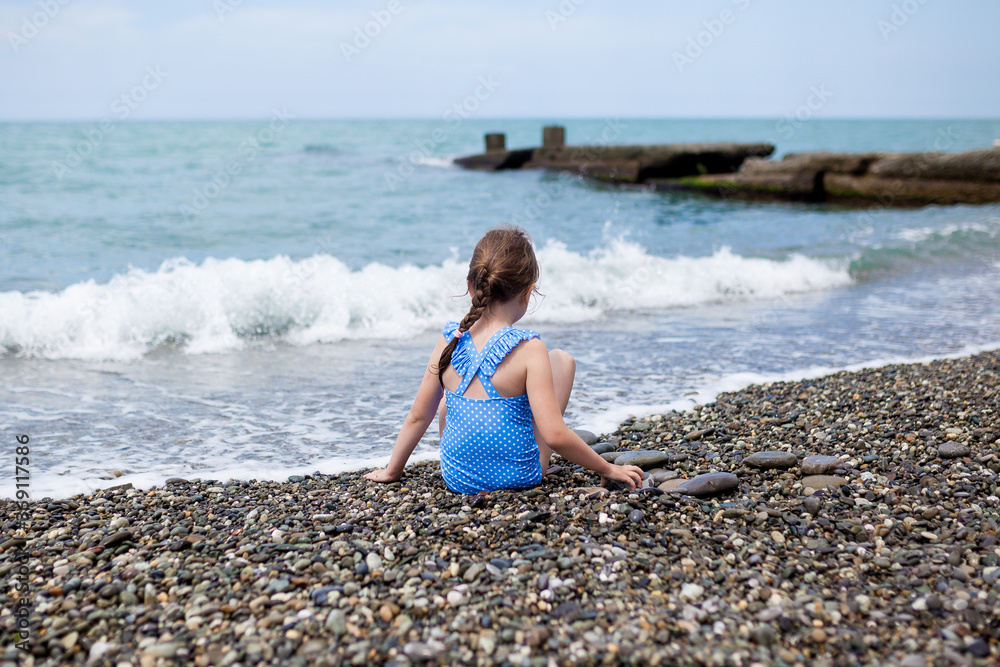 View from behind of toddler 5-6 year old girl in swimsuit sitting on ...