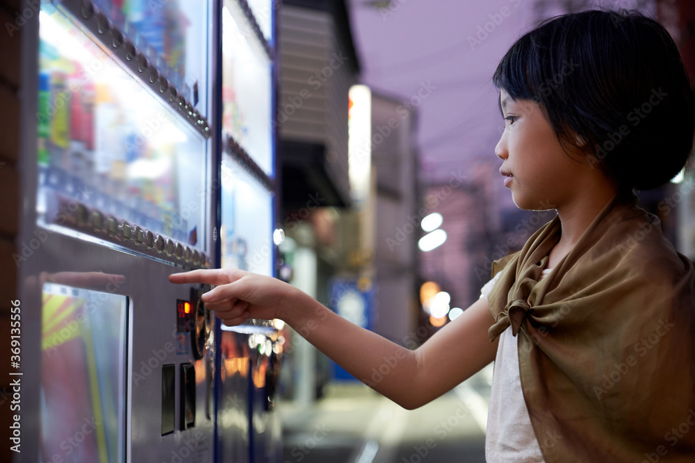 Asian little girl in front of a drink vending machine, on the streets ...