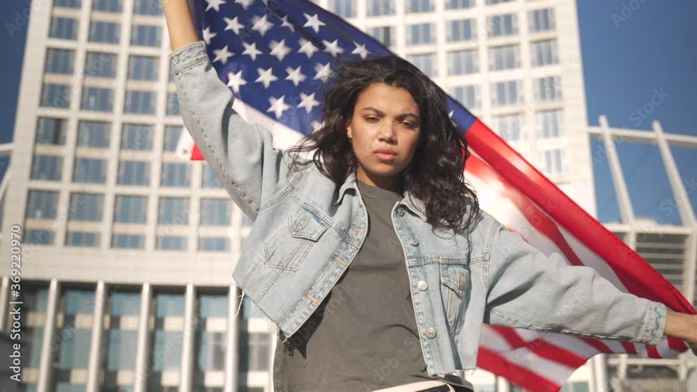 Angry mixed race woman shouting holding USA flag protesting alone on ...