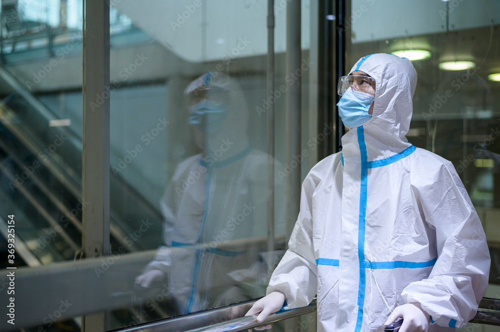 An Asian man is wearing ppe suit in airport elevator , Safety travel ...