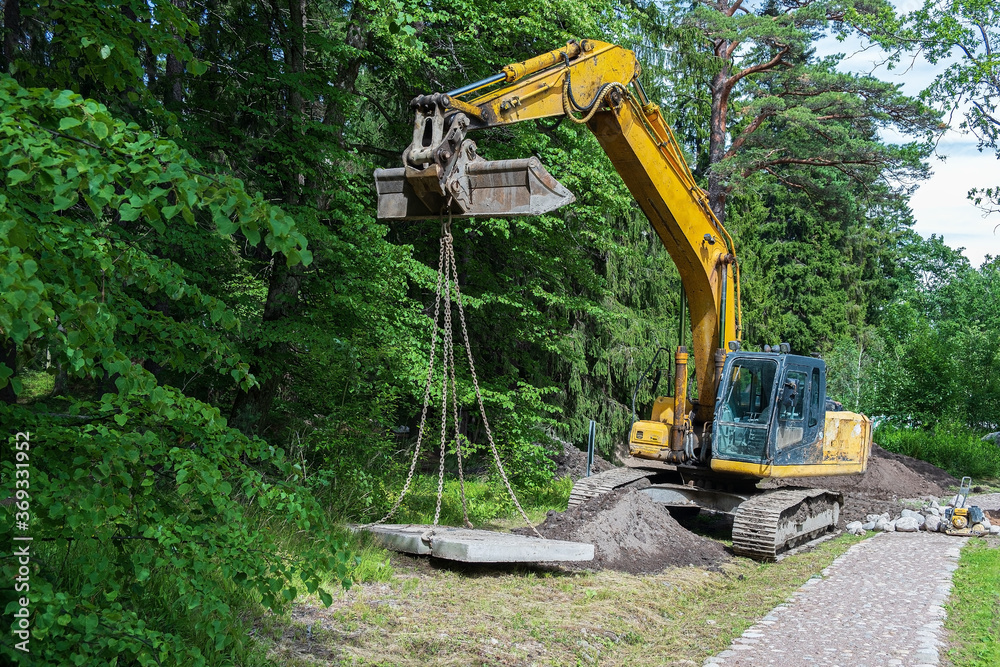 An excavator in the Park lays concrete slabs. Paving the sewer line ...