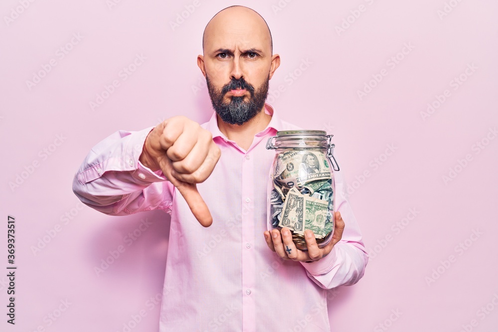 Young handsome man holding jar with savings with angry face, negative ...