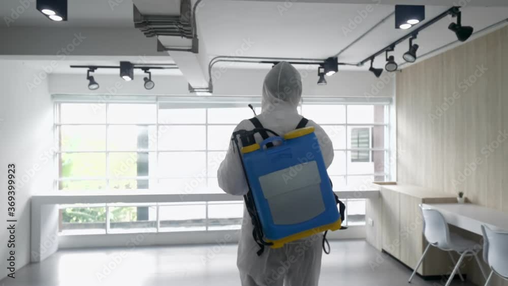 Worker in personal protective equipment (ppe) suit cleaning in building ...