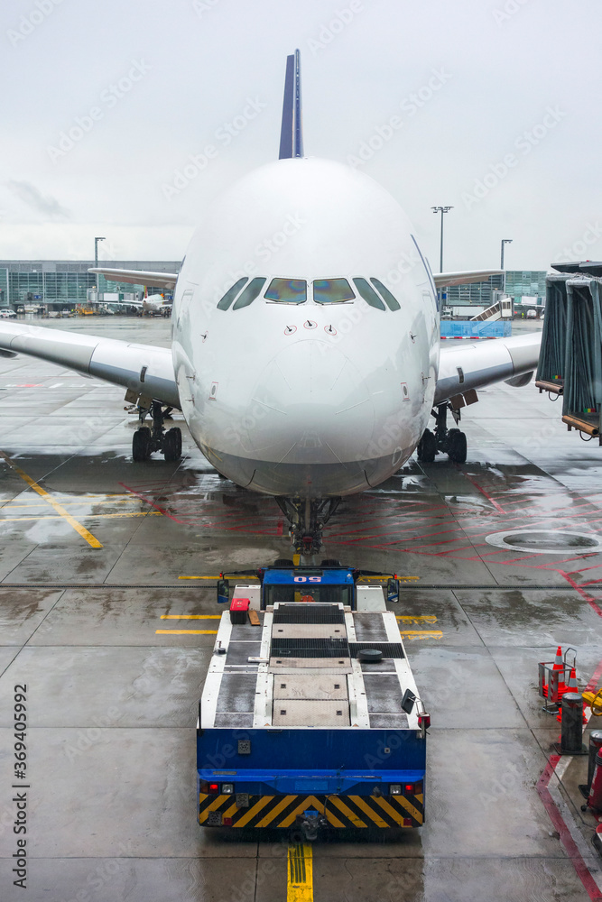 Pushback tug and a large airplane at an airport Stock Photo | Adobe Stock