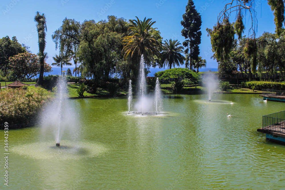 Una fuentes de agua dulce en un parque con arboles de hoja verde y un ...