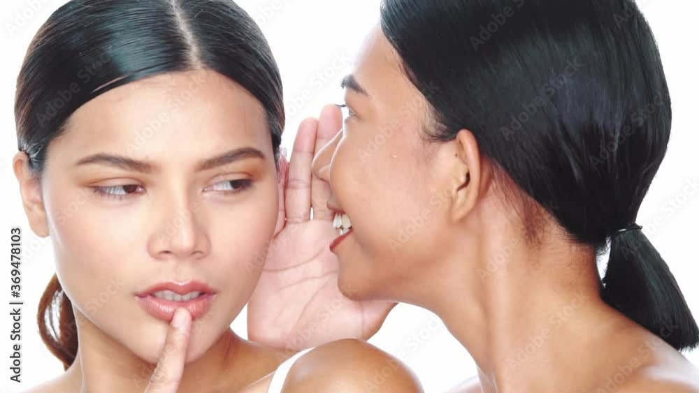 Closeup faces ot two beautiful Asian women gossiping over white background. Friend telling a ...