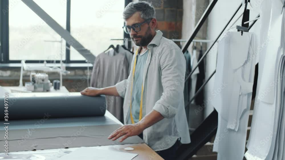 Handsome male tailor using chalk while outlining sewing pattern ...