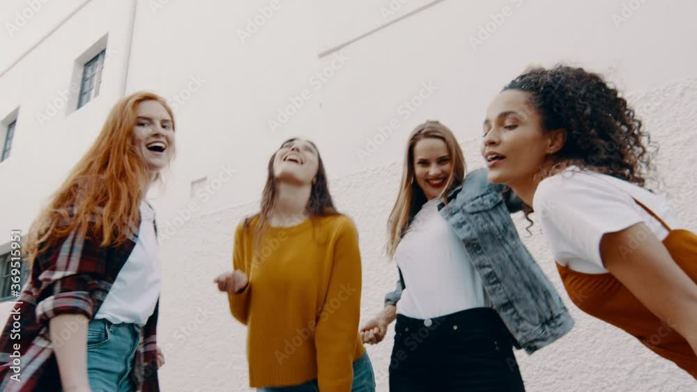 Group of female friends dancing together and blowing confetti. Group of ...