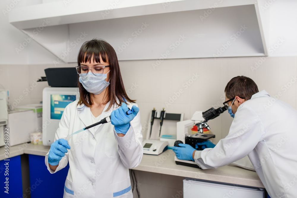 In the hospital laboratories working process, a young woman doctor is ...
