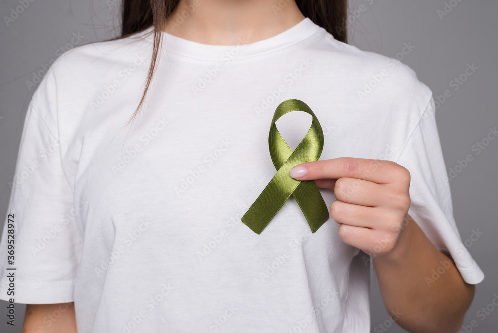 Green ribbon a symbol of cancer isolated on gray background Stock Photo ...