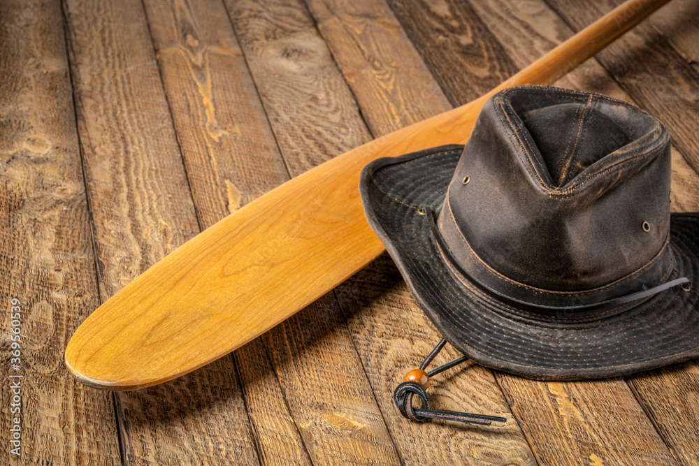 blade of wooden canoe paddle (beaver tail) and outback oilskin hat ...