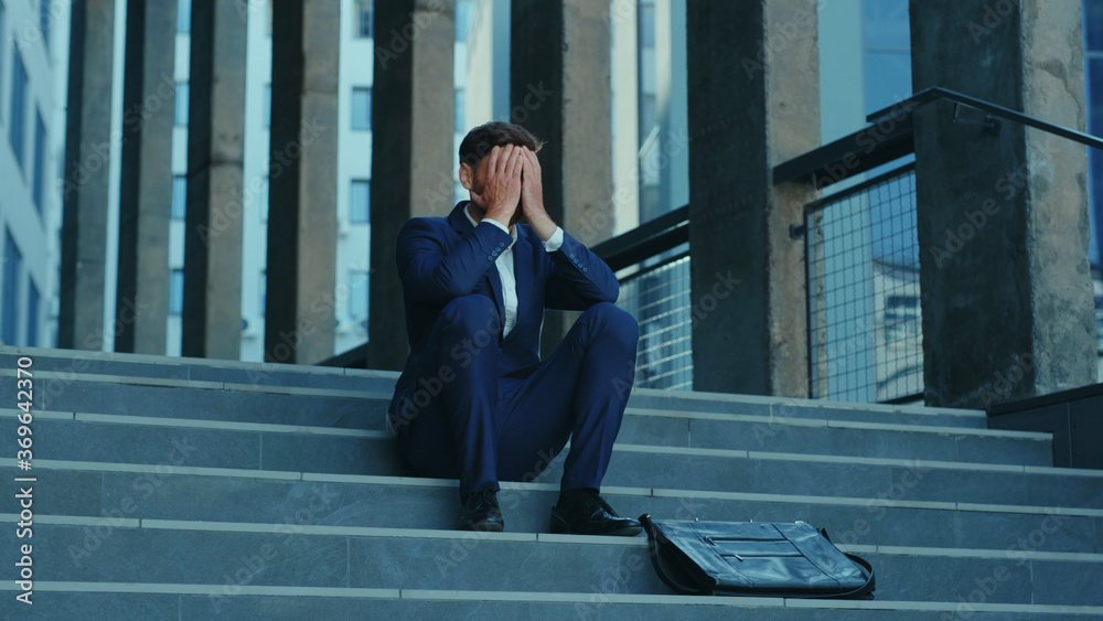 Fired corporate executive crying on stairs of office building outside ...