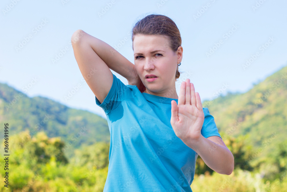 Young beautiful woman, sweating girl with a wet spot on T-shirt because ...