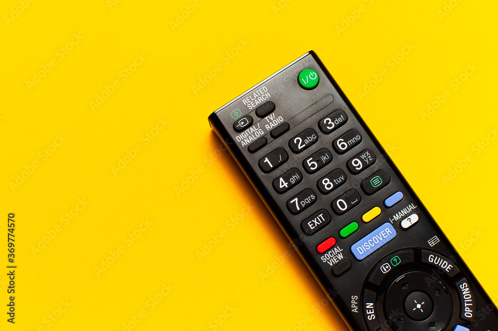 Black TV remote control on bright yellow background flat lay top view ...