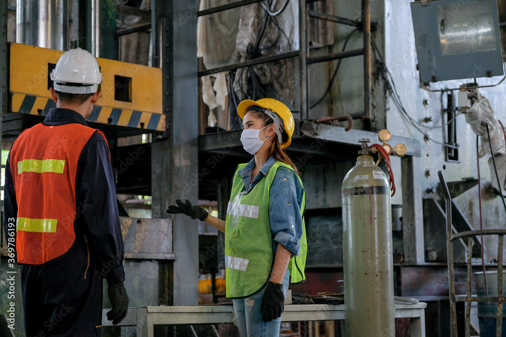 Factory worker man and woman with hygiene mask discuss together in ...