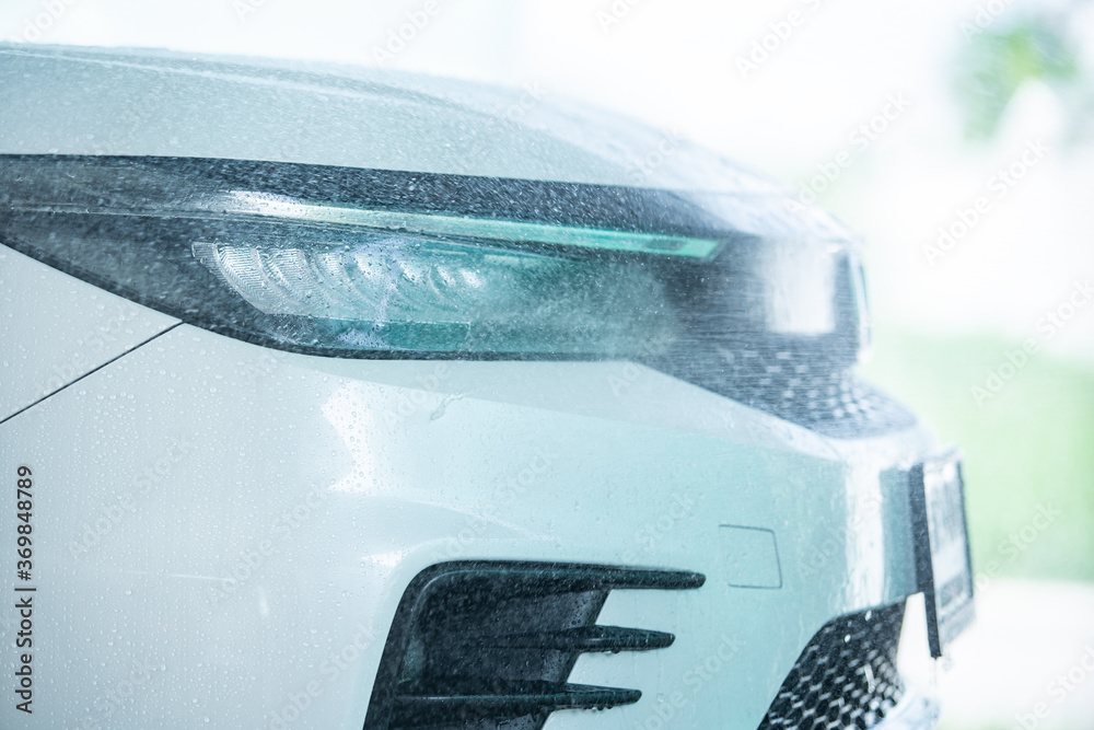 Man worker in garage using a high pressurised foam injector spraying on ...