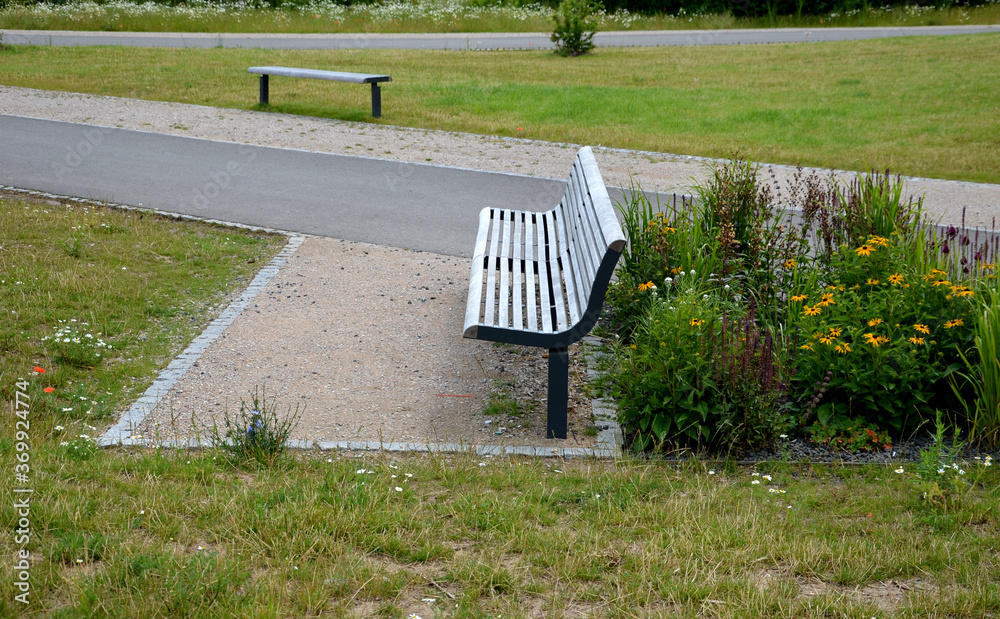 wooden modern park bench with a metal relief structure on one leg ...
