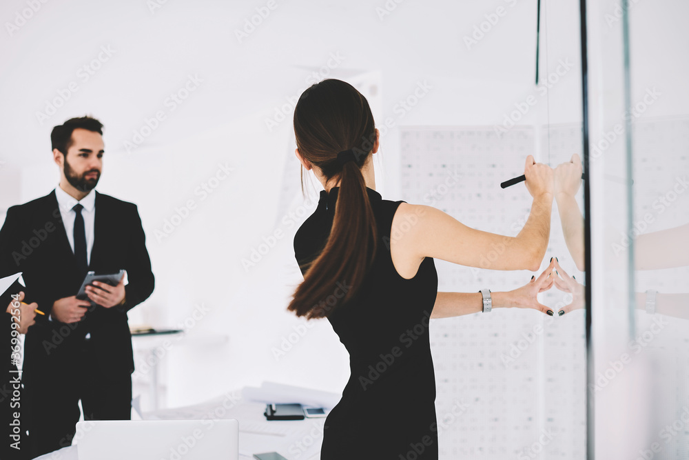 Back view of skilled female business coach explaining new concept of ...