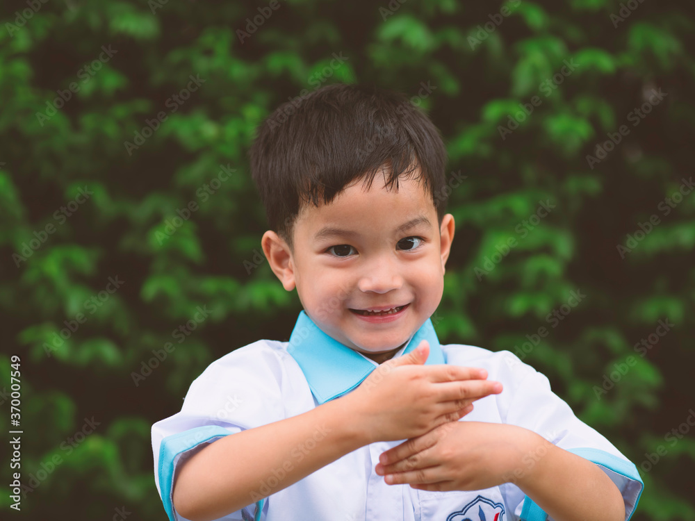 Headshot portrait of preschool Asian boy in uniform happy in backyard ...