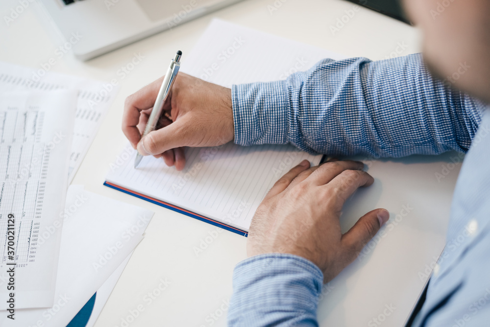 Man holding pen pencil in hand filling writing taking notes into notes ...