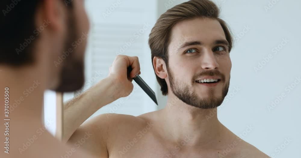 Mirror reflection happy handsome man styling hair with comb, satisfied ...