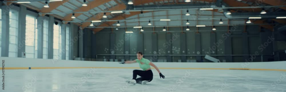 Female ice figure skater falls on ice while practicing jumps on the ...