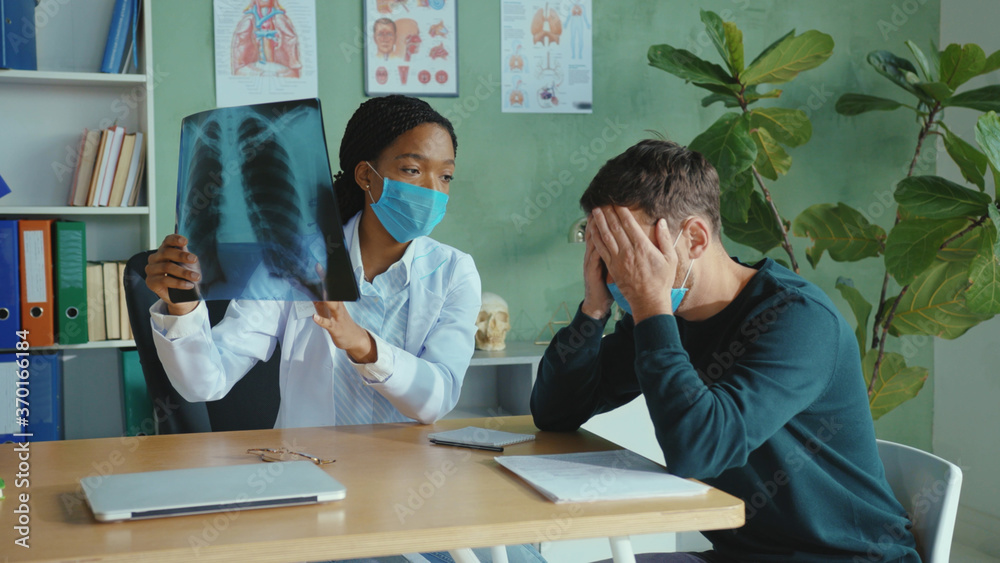 Female doctor in medical mask welcoming her patient, analyzing x-ray ...