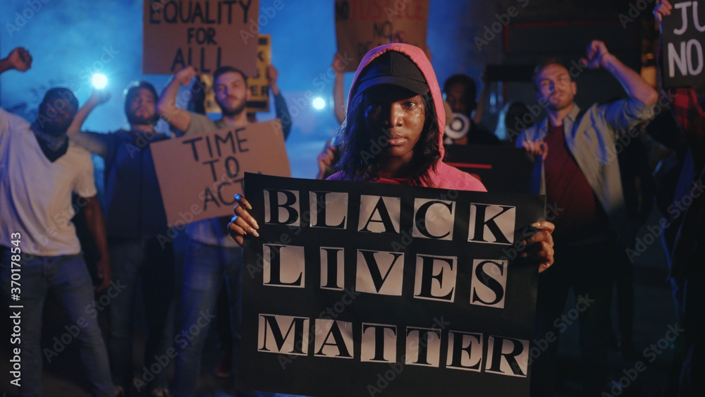 Confident black woman holds invocatory poster, standing in crowd of ...