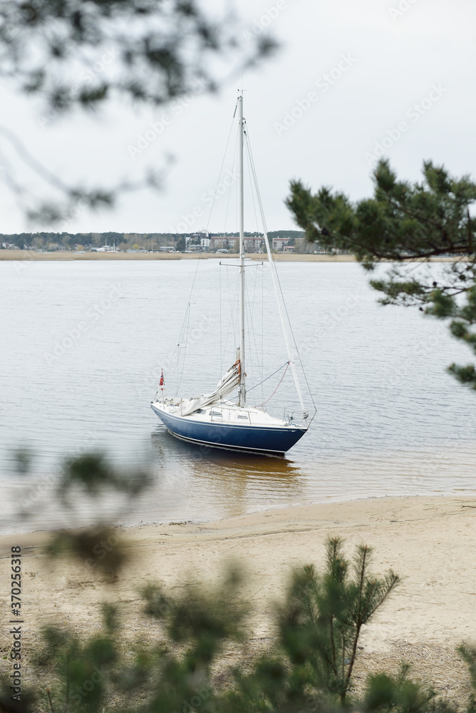Blue sloop rigged yacht anchored in the shallow water near the sandy ...