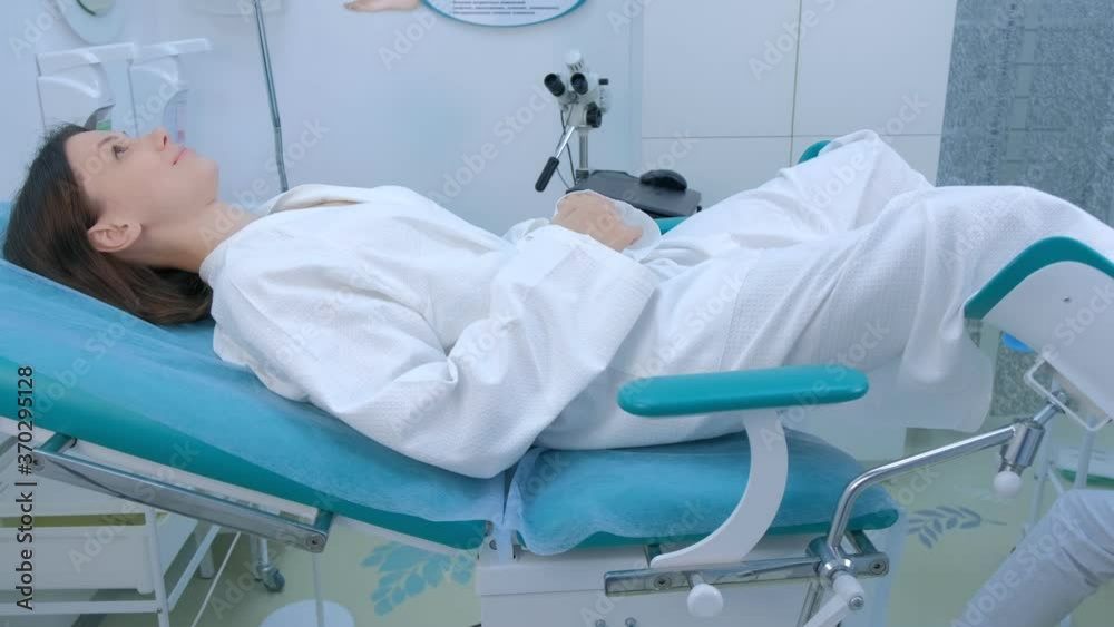 Young patient woman in gynecological chair in clinic, side view. Modern ...