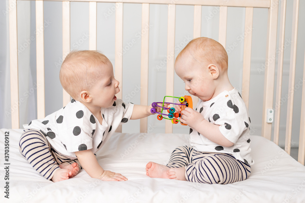 two twin babies 8 months old play in the crib, early development of ...