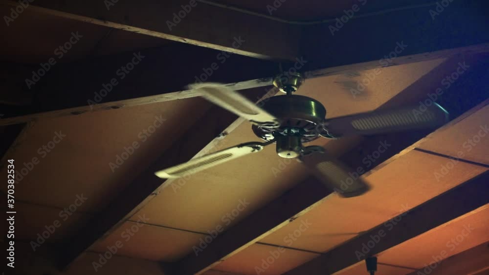 An overhead fan spinning slowly on a timber ceiling amidst wooden ...
