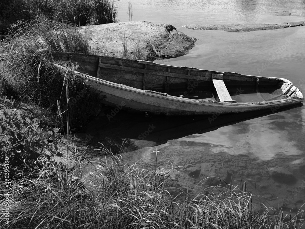Monochrome photograph of a sunken small boat in a harbour. It is an old ...