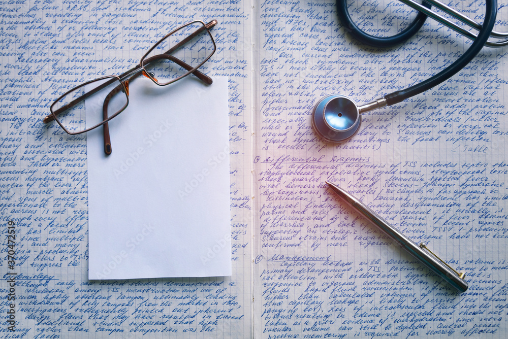 Hand-written medical text Stethoscope, ballpen and spectacles over hand ...