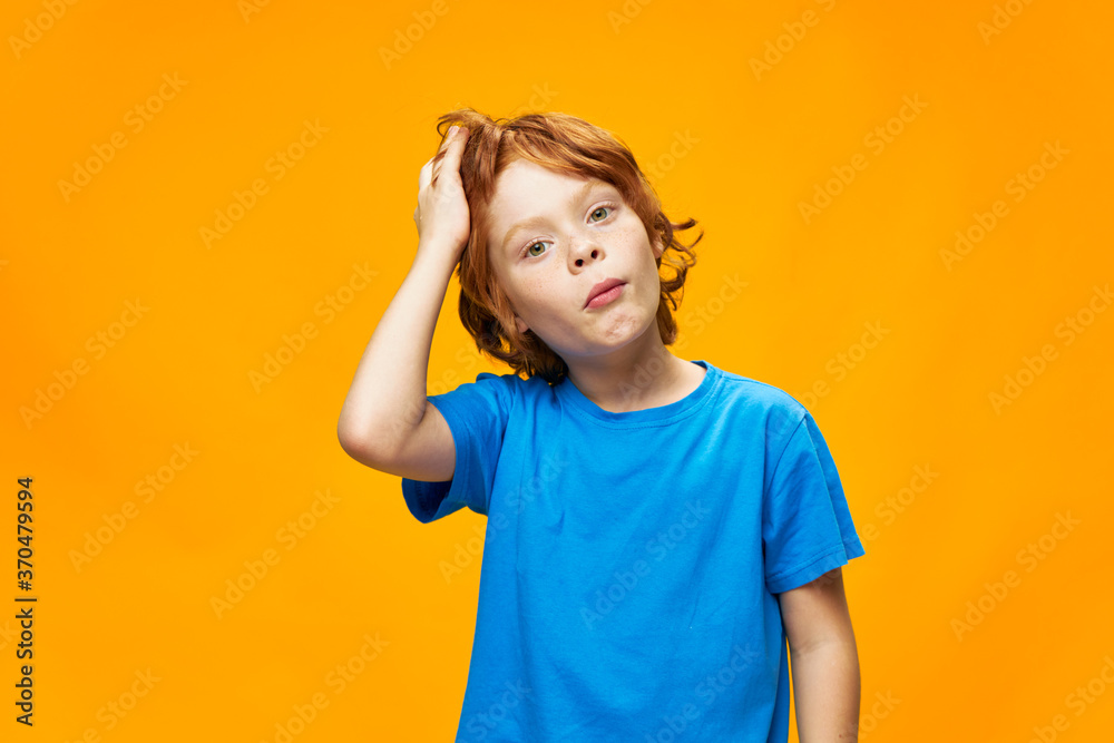 boy red hair blue t-shirt yellow isolated background freckles and ...