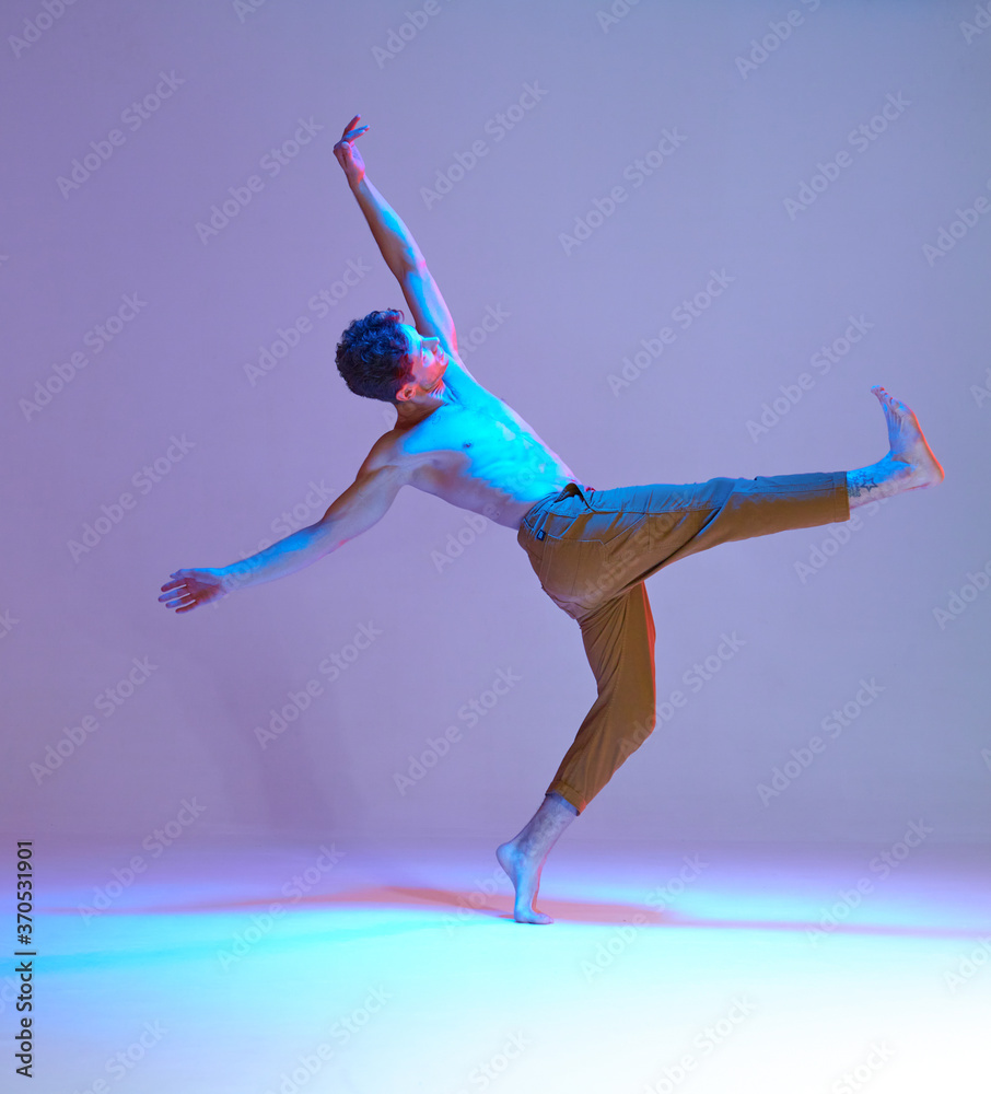 Cool guy breakdancer dancing hip-hop in lilac neon light in studio ...