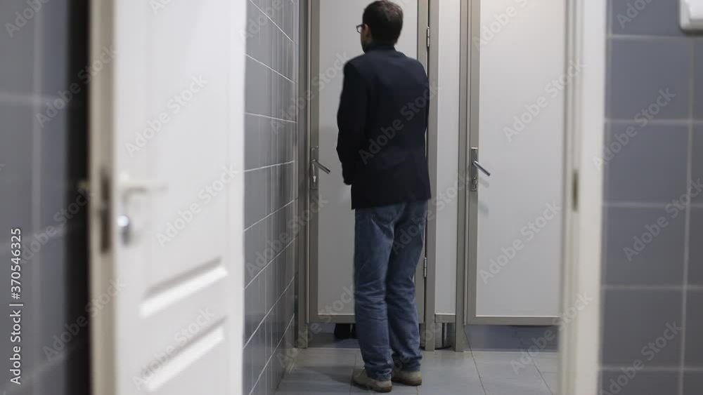 Man with urinary incontinence in public restroom near closed toilet ...