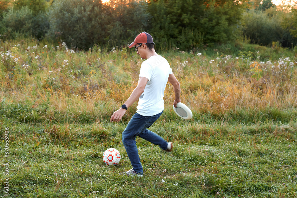 Cheerful Handsome guy kicks the ball, smiling amused as playing ...