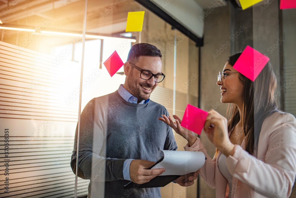 Business people looking at post it notes on notice board. Brainstorming ...
